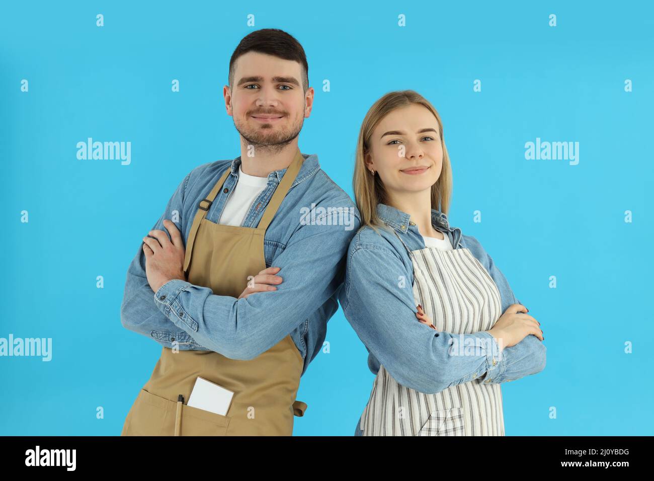Young waiter and waitress on blue background Stock Photo - Alamy