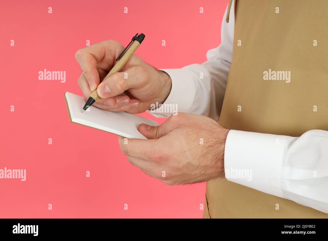 Waiter man write order in notebook on pink background Stock Photo - Alamy