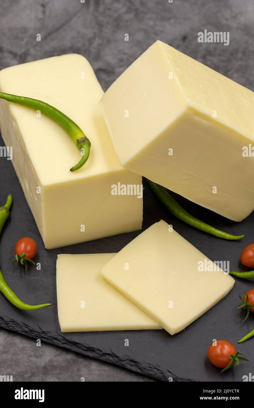 Cheddar cheese or kashkaval cheese on dark background. Cheese slices on ...