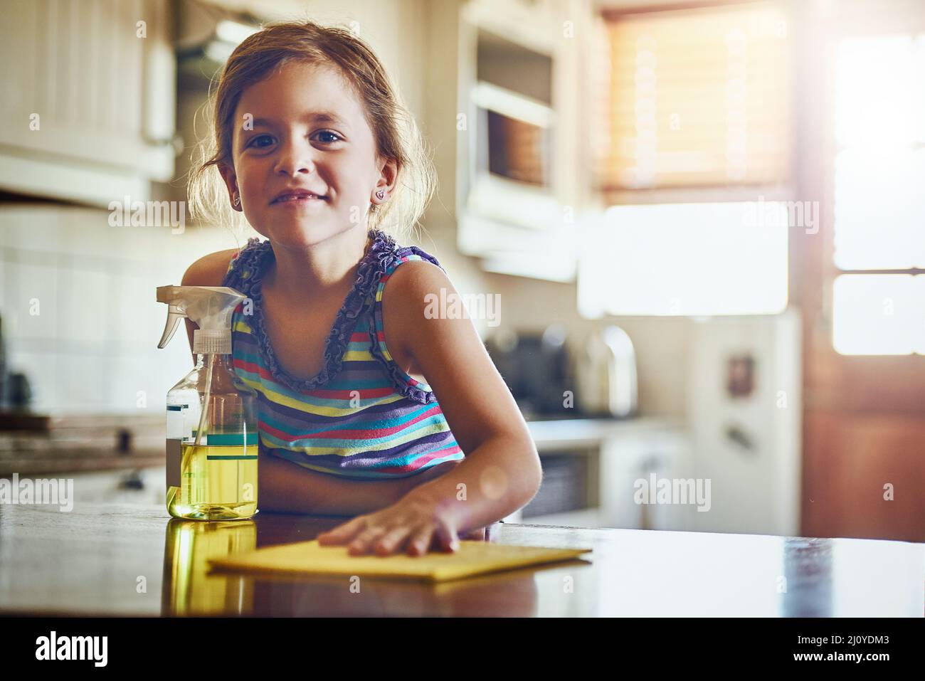 Keeping things clean. Portrait of a little girl cleaning a kitchen ...