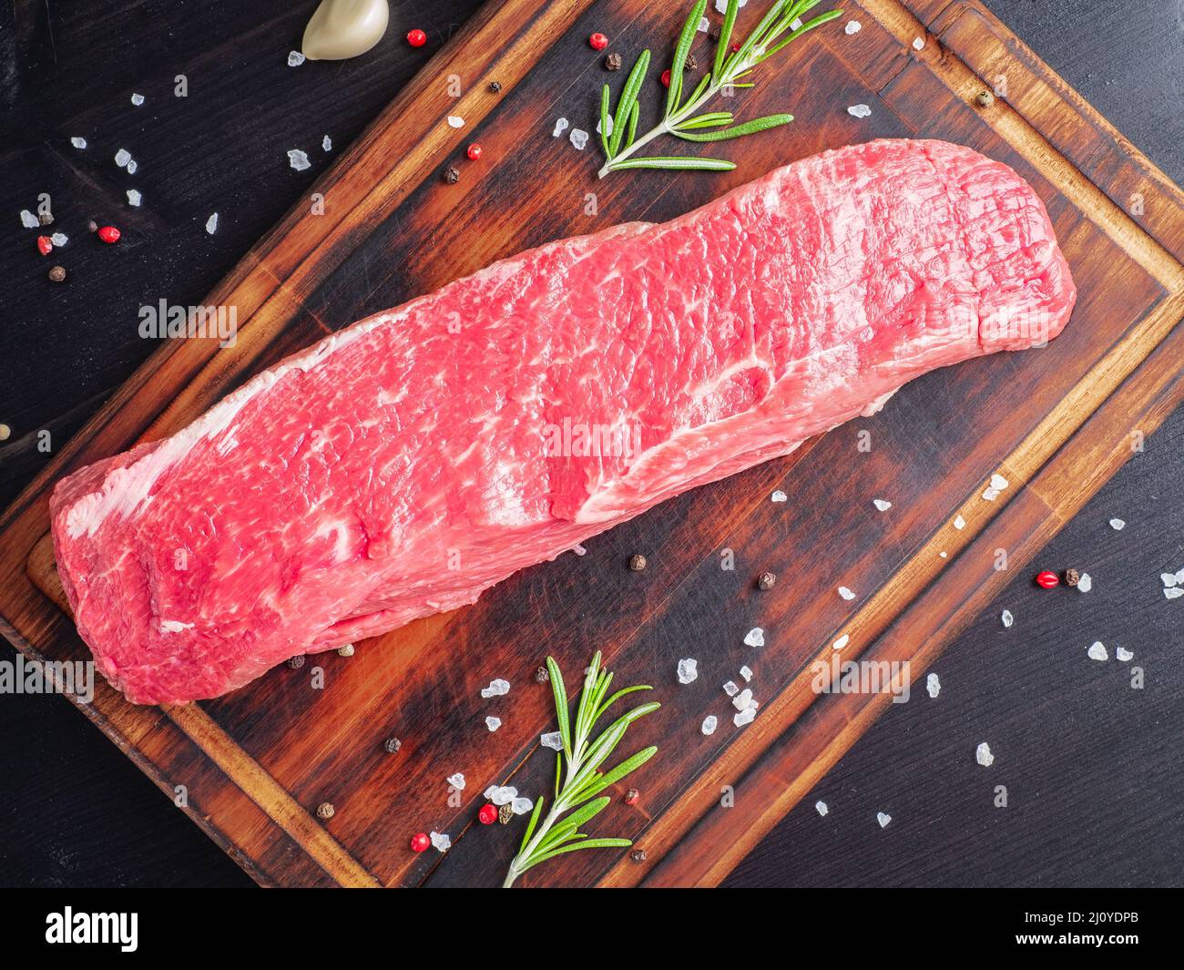 Raw meat, beef steak with seasoning on chopping board on dark ...