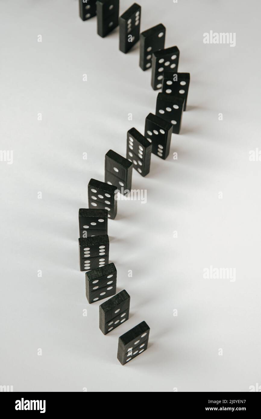 Black dominoes chain on a white table background. Domino effect concept ...