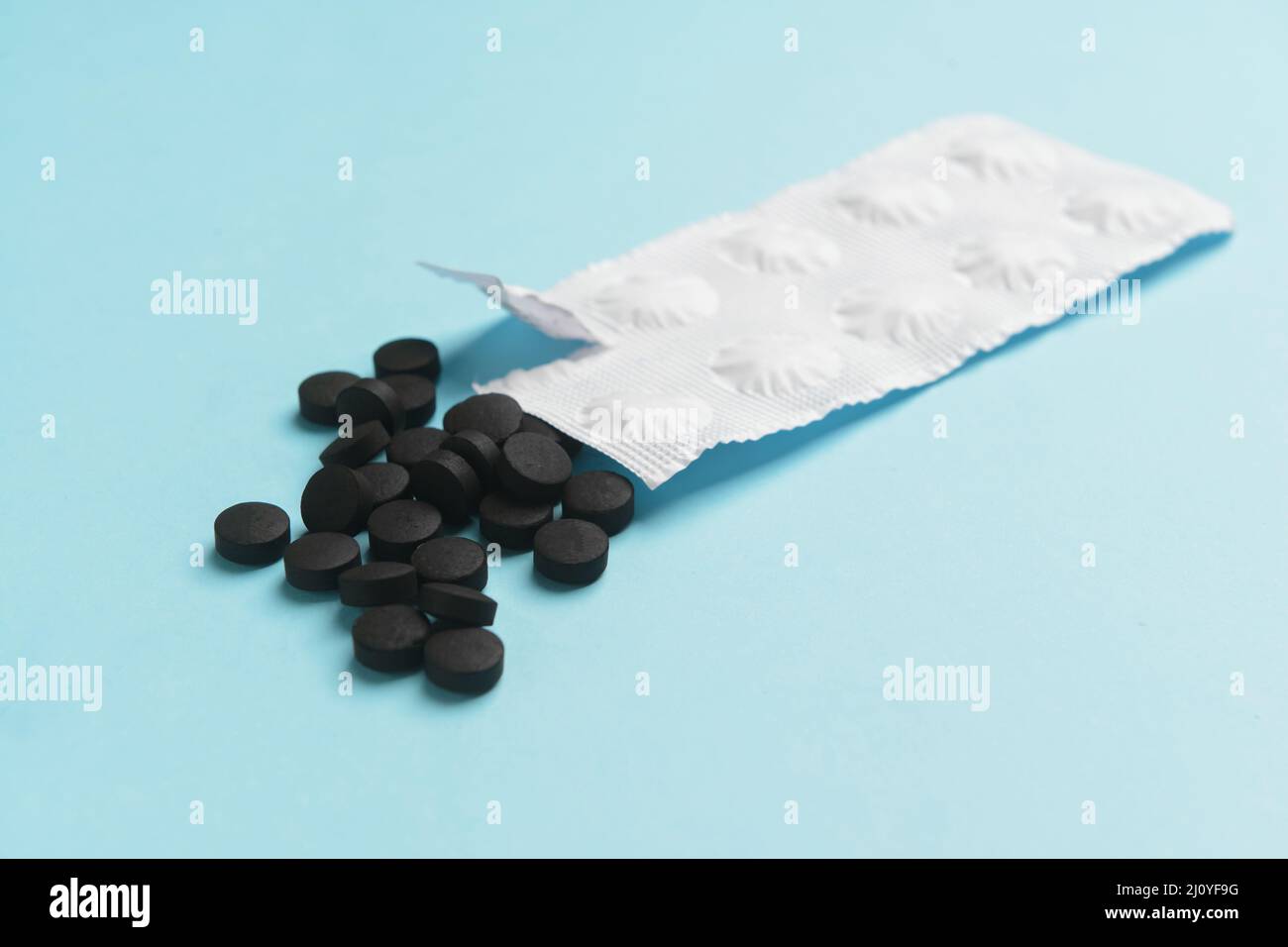 Activated carbon pills and paper packing on blue background Stock Photo ...