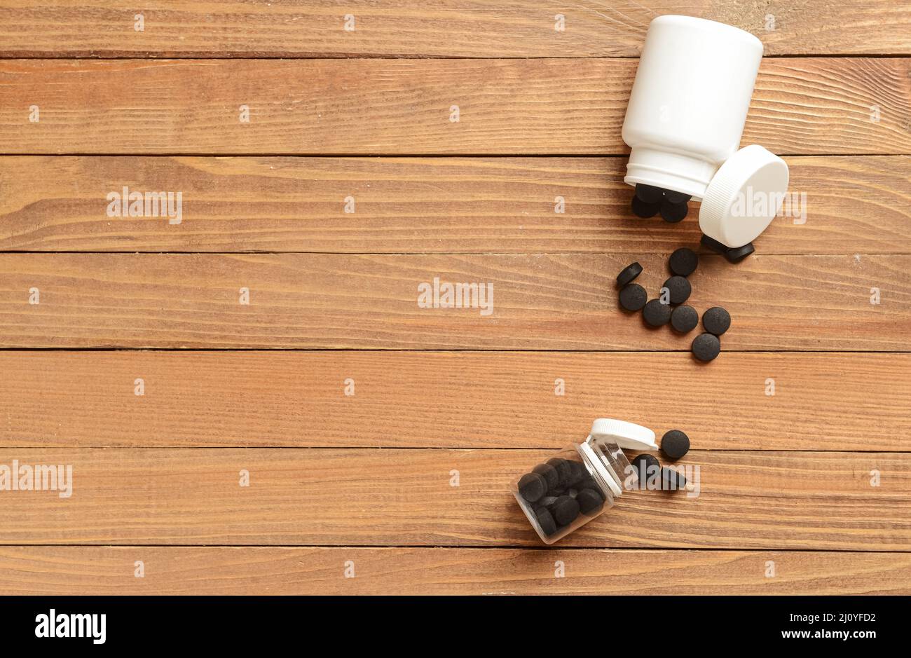 Bottles of activated carbon pills on wooden background Stock Photo - Alamy