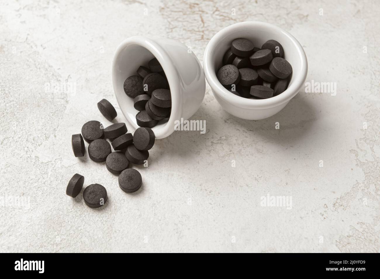Bowls of activated carbon pills on light background Stock Photo - Alamy