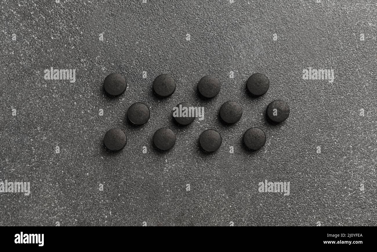 Activated carbon pills on dark background Stock Photo - Alamy