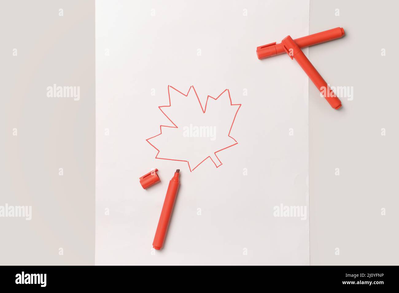 Paper sheet with drawn maple leaf and red markers on light background ...