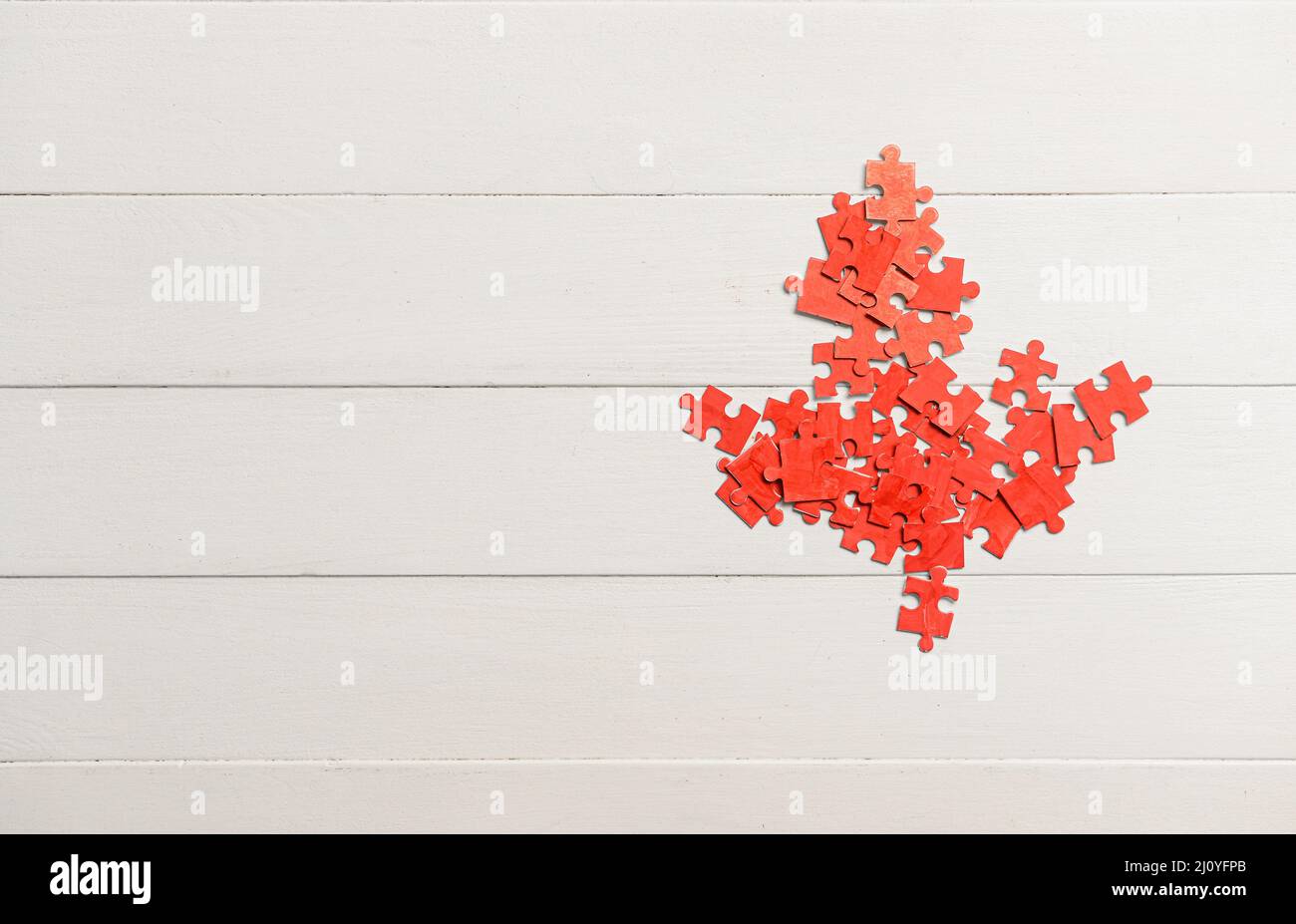 Maple leaf made of red puzzle pieces on white wooden background ...