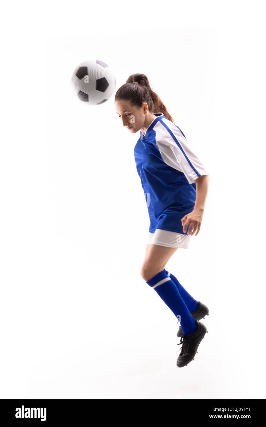 Caucasian young female soccer player heading soccer ball while playing ...