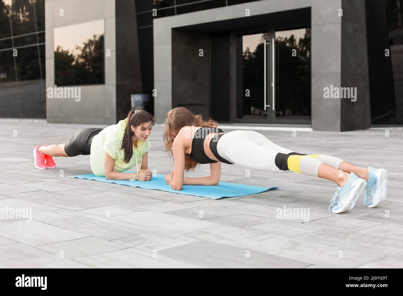 Beautiful young women doing plank outdoors Stock Photo - Alamy