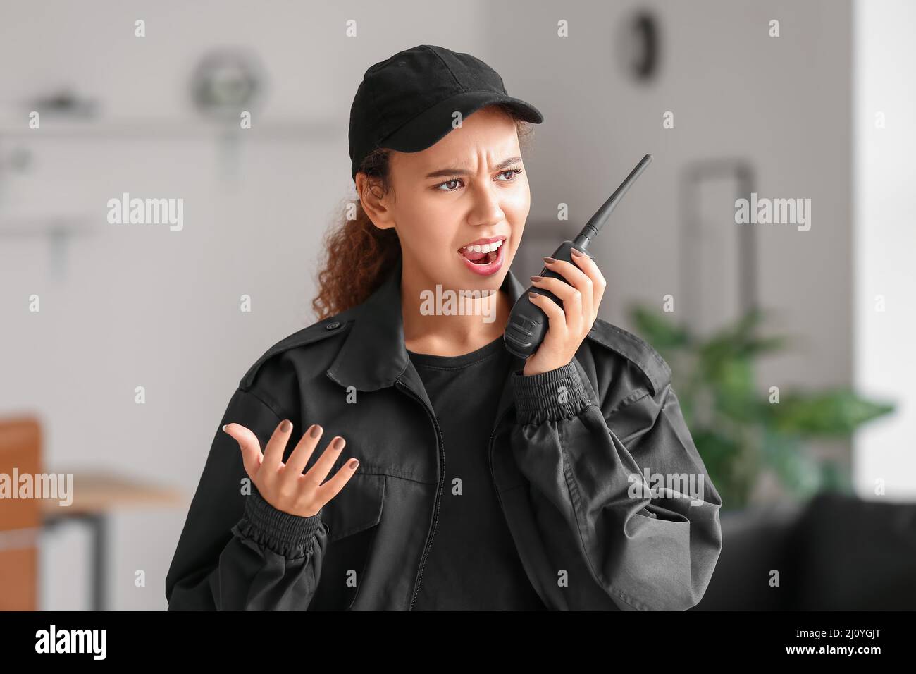 Angry African-American female security guard with radio transmitter in ...