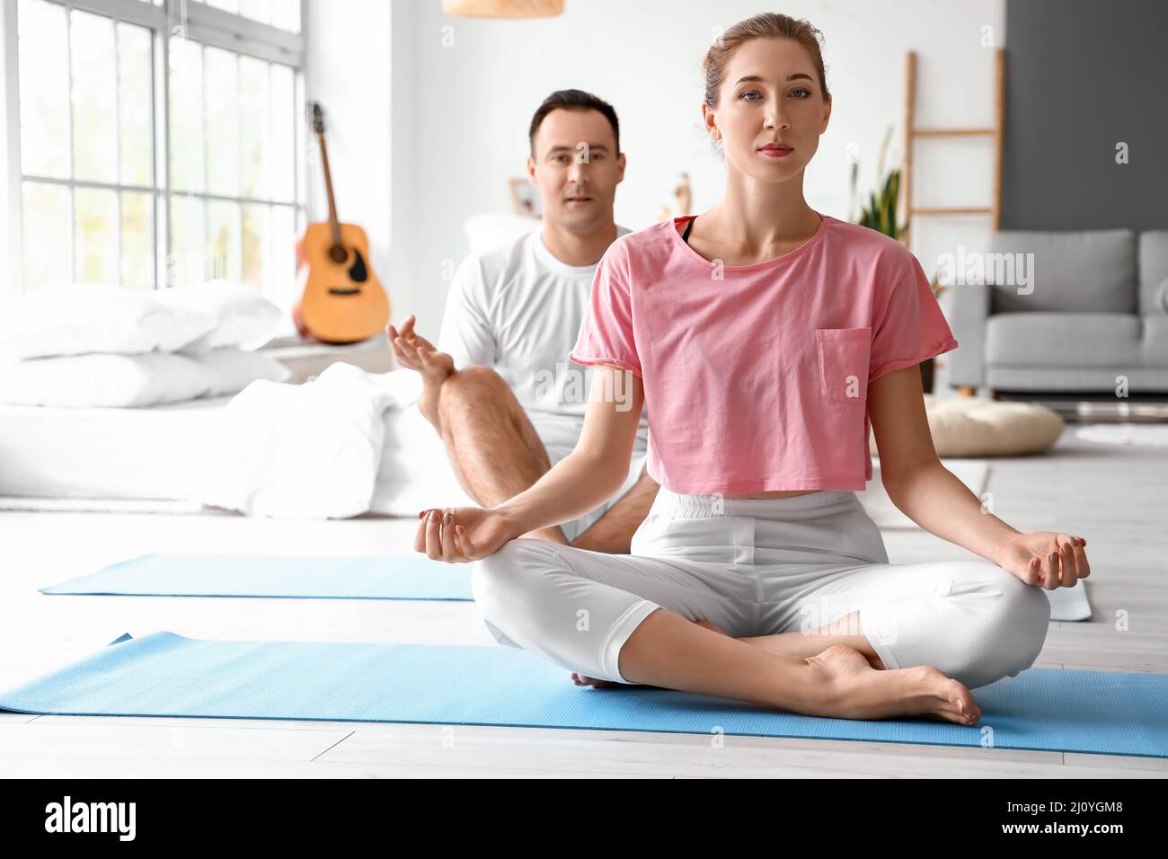 Sporty couple meditating together at home Stock Photo - Alamy
