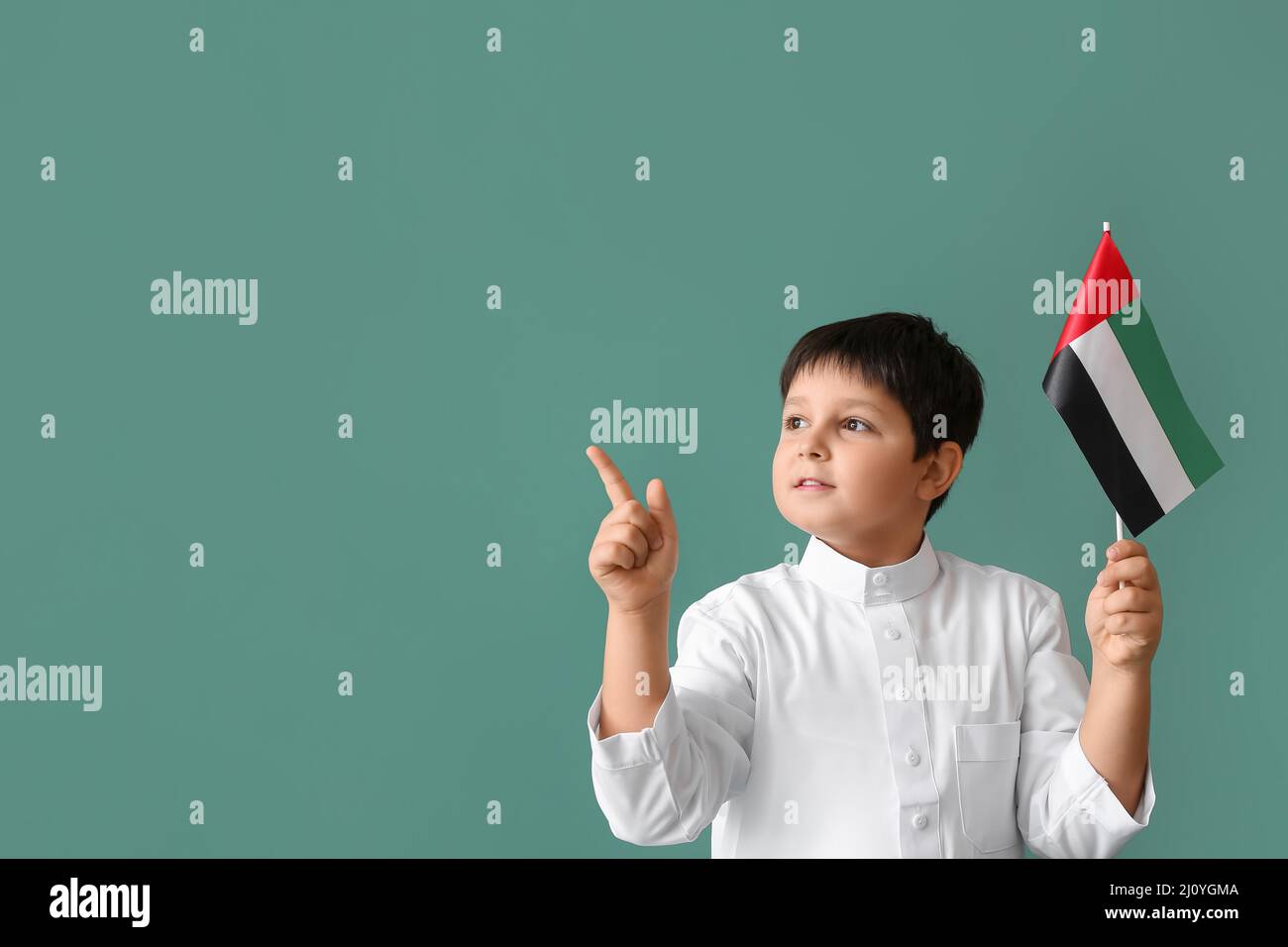 Cute little boy with national flag of UAE showing something on color ...