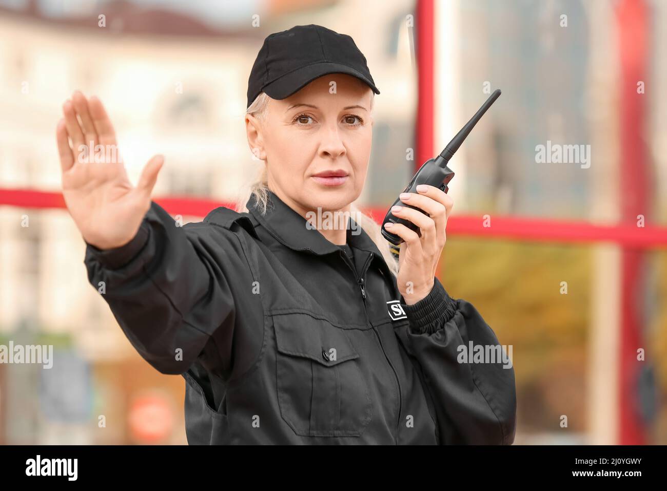 Female security guard showing stop gesture outdoors Stock Photo - Alamy