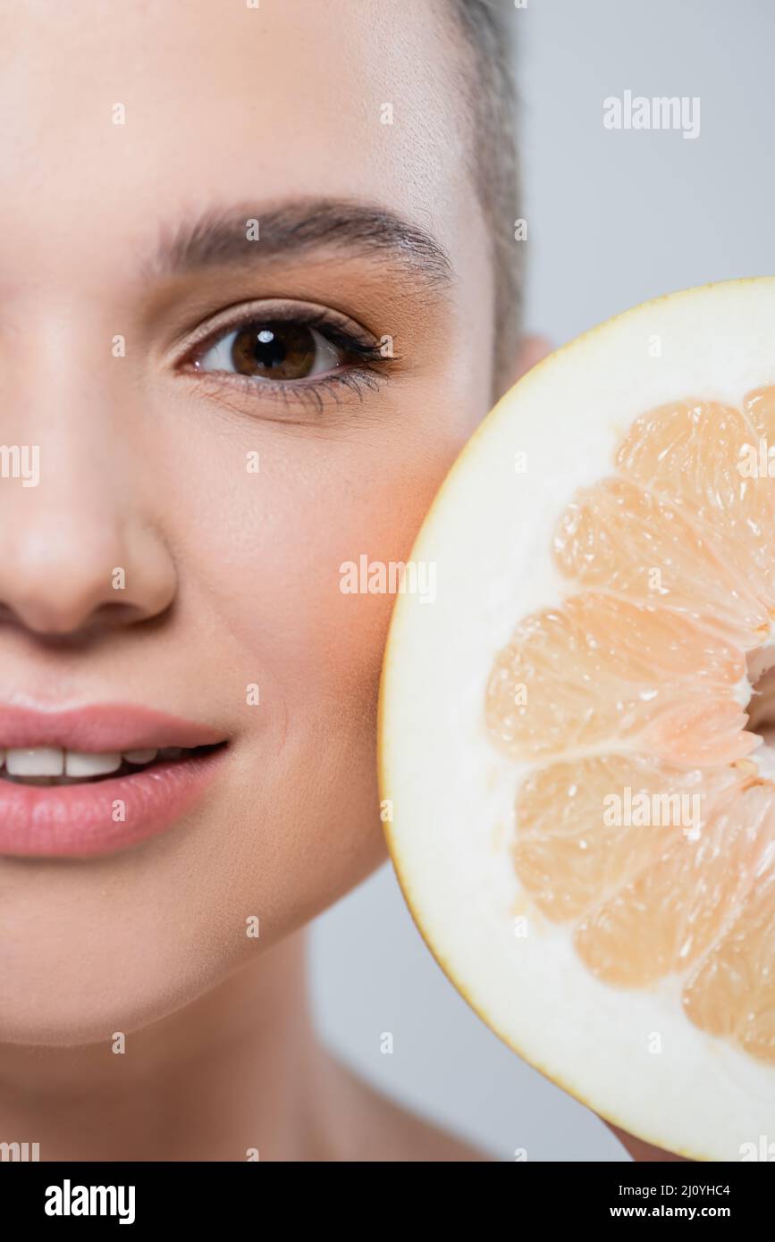 close up view of grapefruit half near cropped female face isolated on ...
