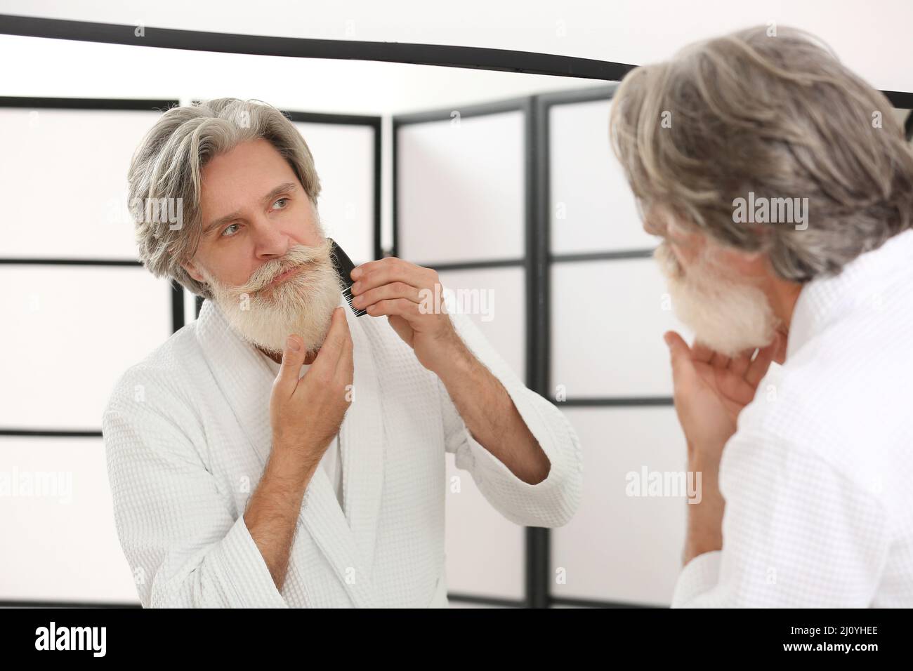 Mature man taking care of his beard and mustache in bathroom Stock ...