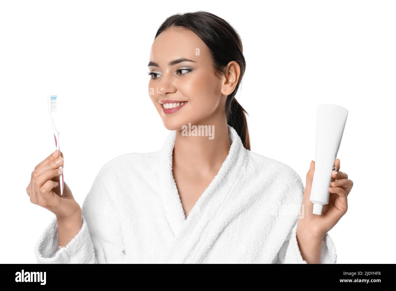 Smiling young woman with tooth paste and brush on white background ...