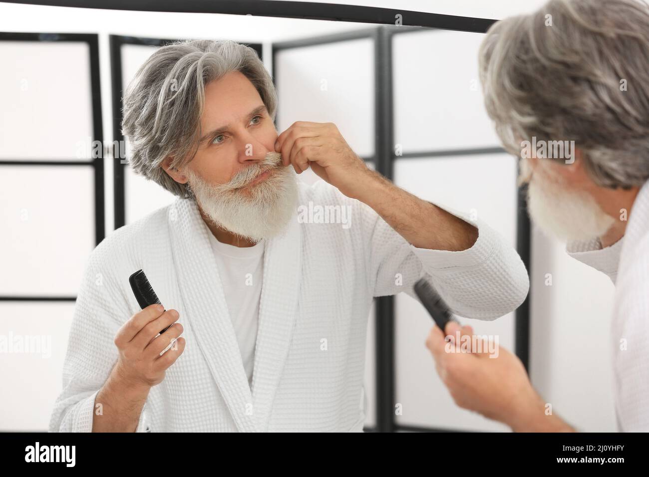 Mature man taking care of his beard and mustache in bathroom Stock ...