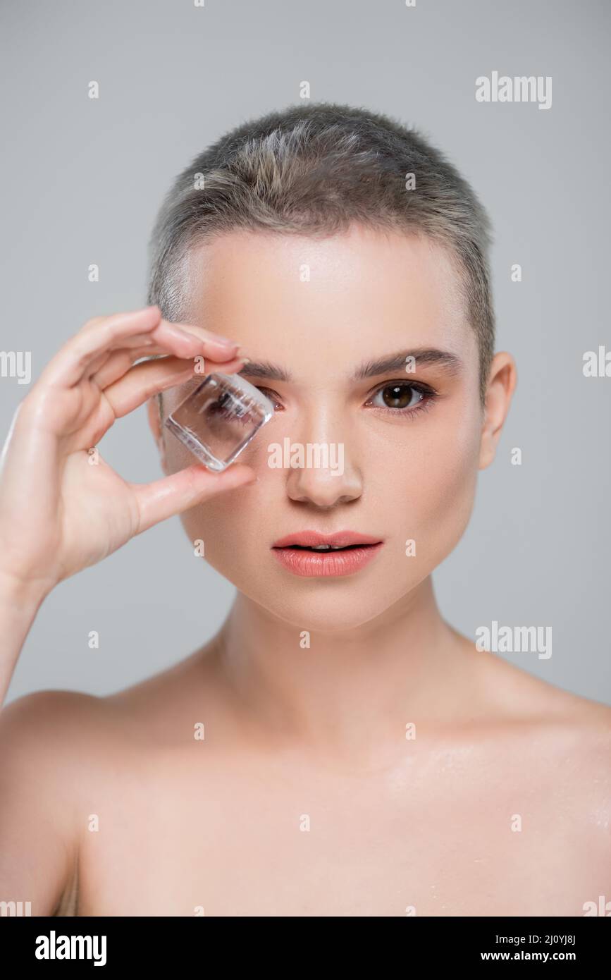 young woman with perfect skin holding ice cube near face isolated on ...