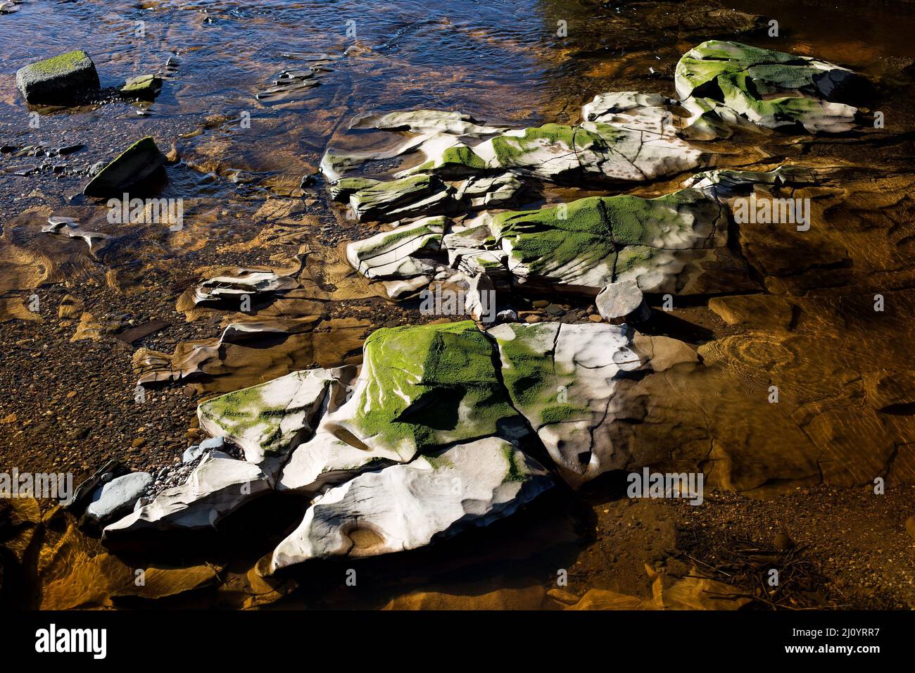 Rock formation and stones in a river bed in low water conditions Stock ...