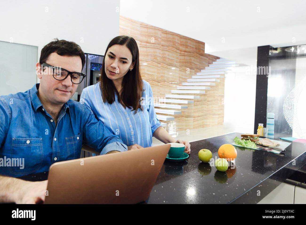 Cheerful intelligent couple working together at home kitchen during ...