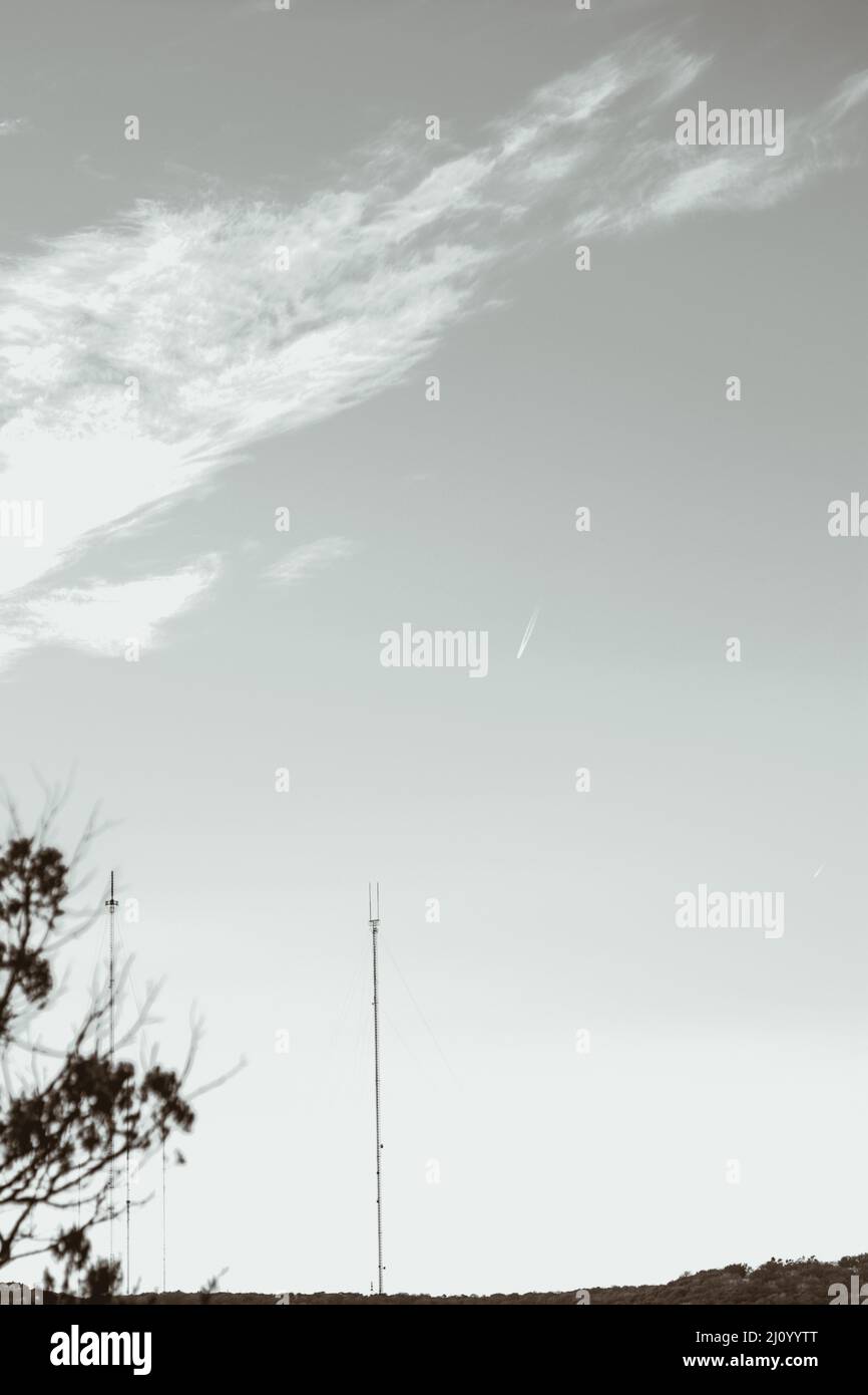 Vertical view of the gray sky with some white clouds and a radio mast ...