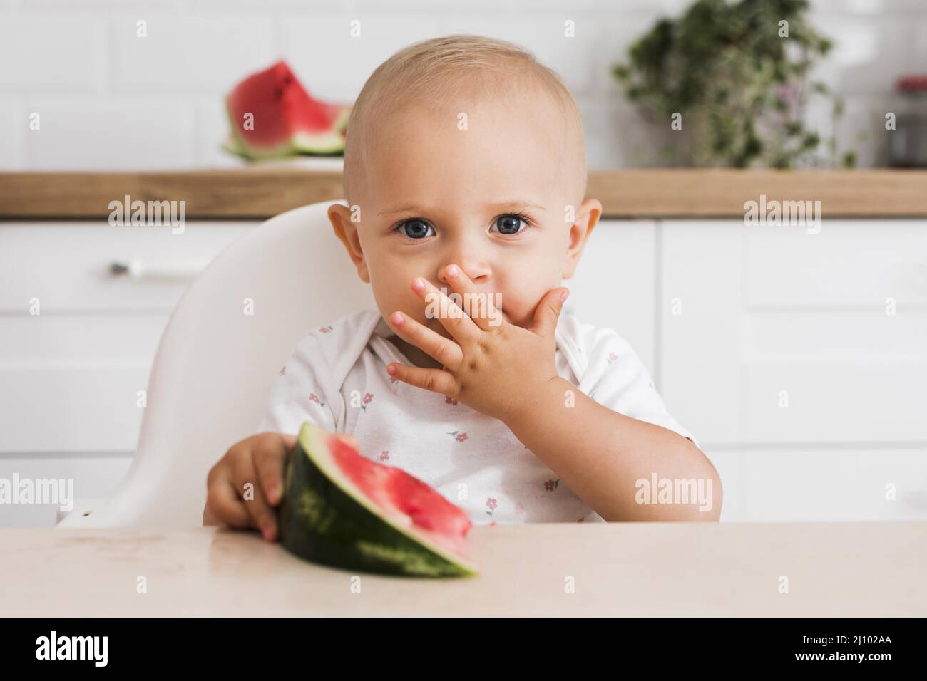 Front view beautiful baby eating watermelon Stock Photo - Alamy