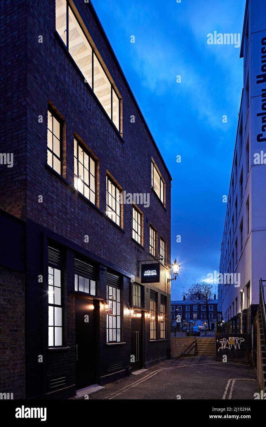 Perspective along building facade at dusk. Symes Mews, London, United ...