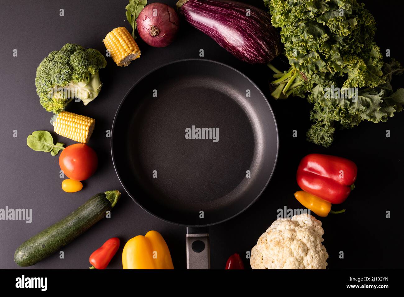 Overhead view of empty frying pan amidst various vegetables on black ...