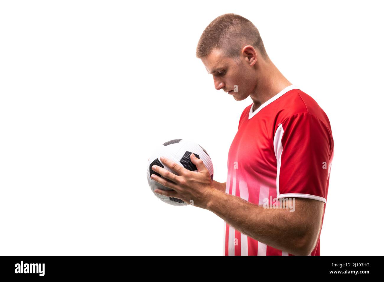 Side view of young male caucasian athlete looking at soccer ball over ...