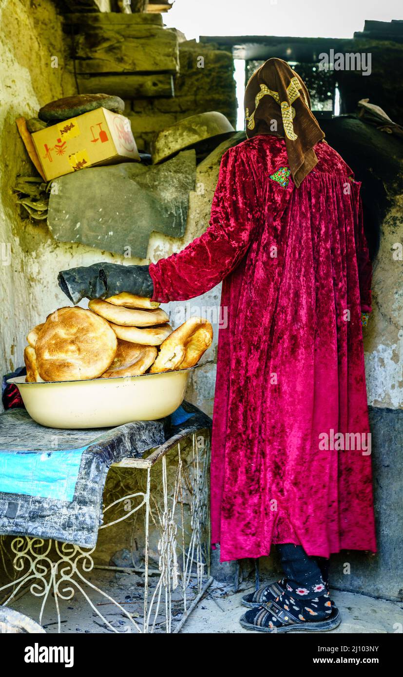 A village woman is baking traditional Tajik bread, non or naan at a ...