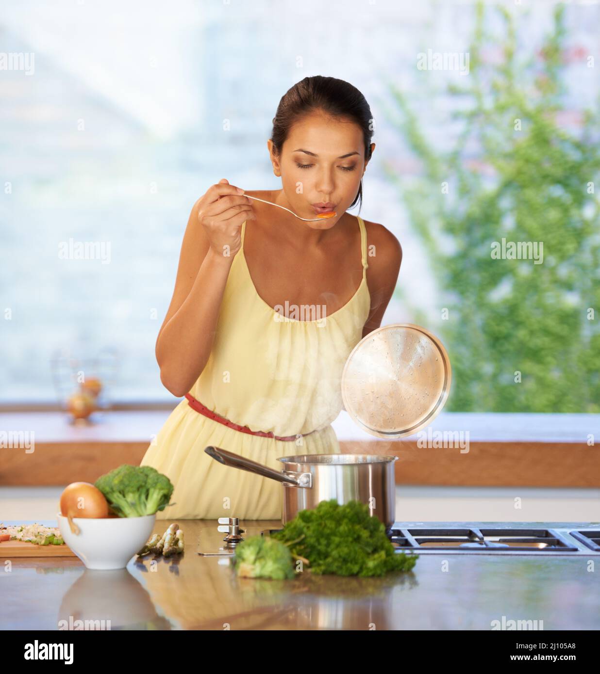 Tasting her creation. A young woman tasting her homemade soup Stock ...