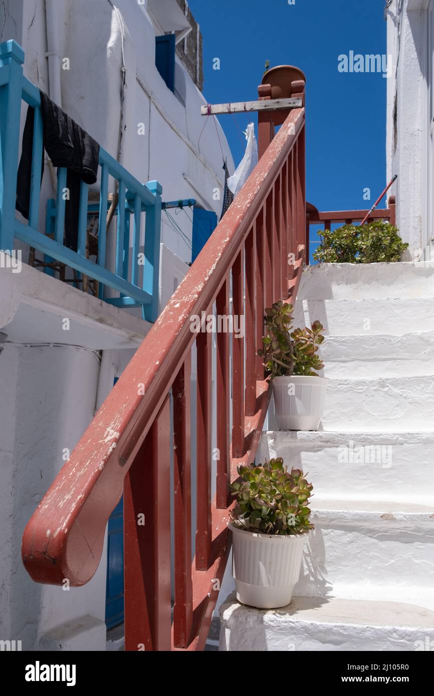 Exterior staircase with faded handrail at Greek island. Pot with plant ...