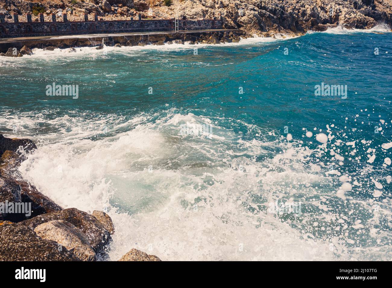Sea water beats against rocky rocks and makes waves with foam, rugged ...