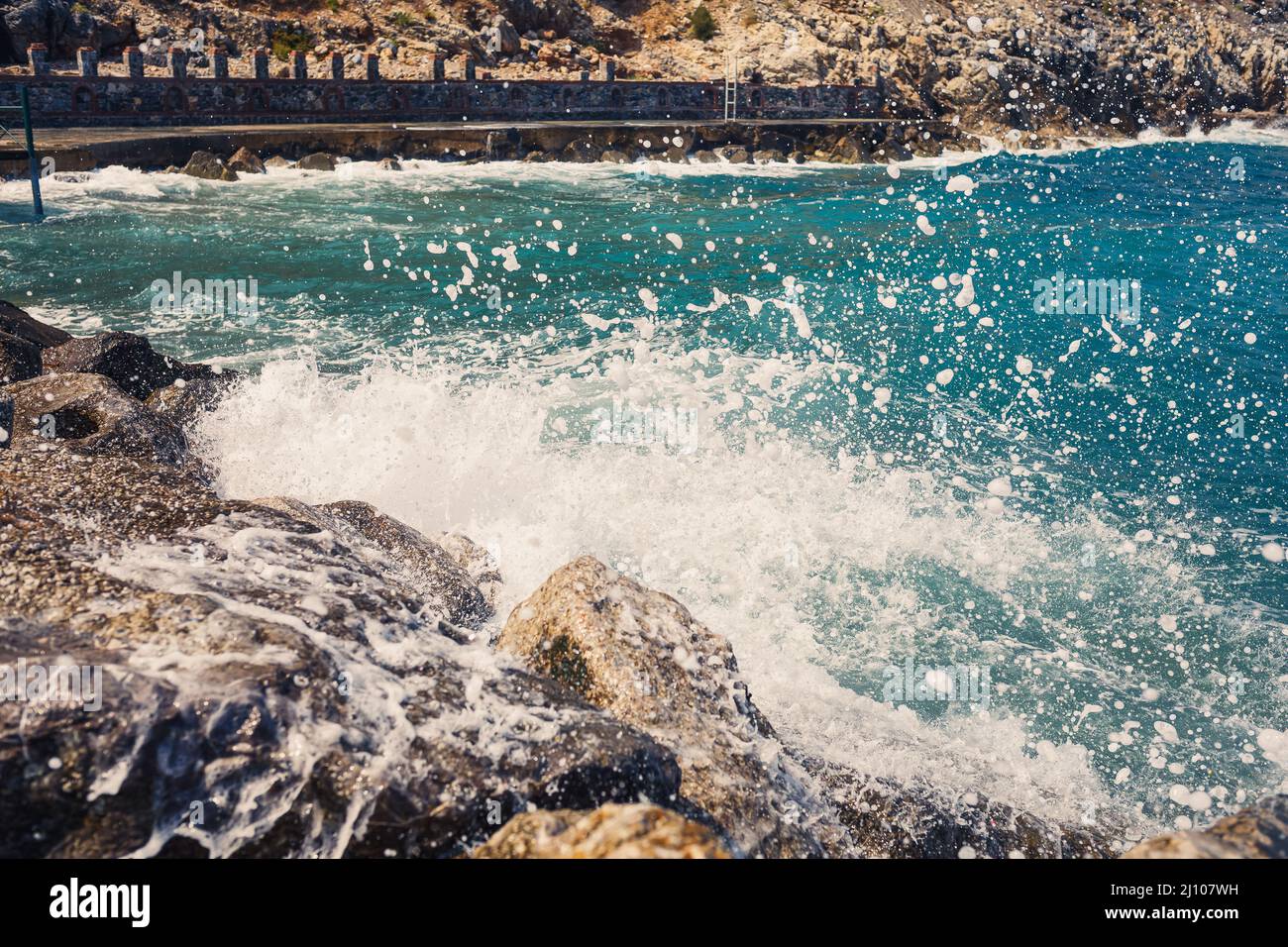 Sea water beats against rocky rocks and makes waves with foam, rugged ...