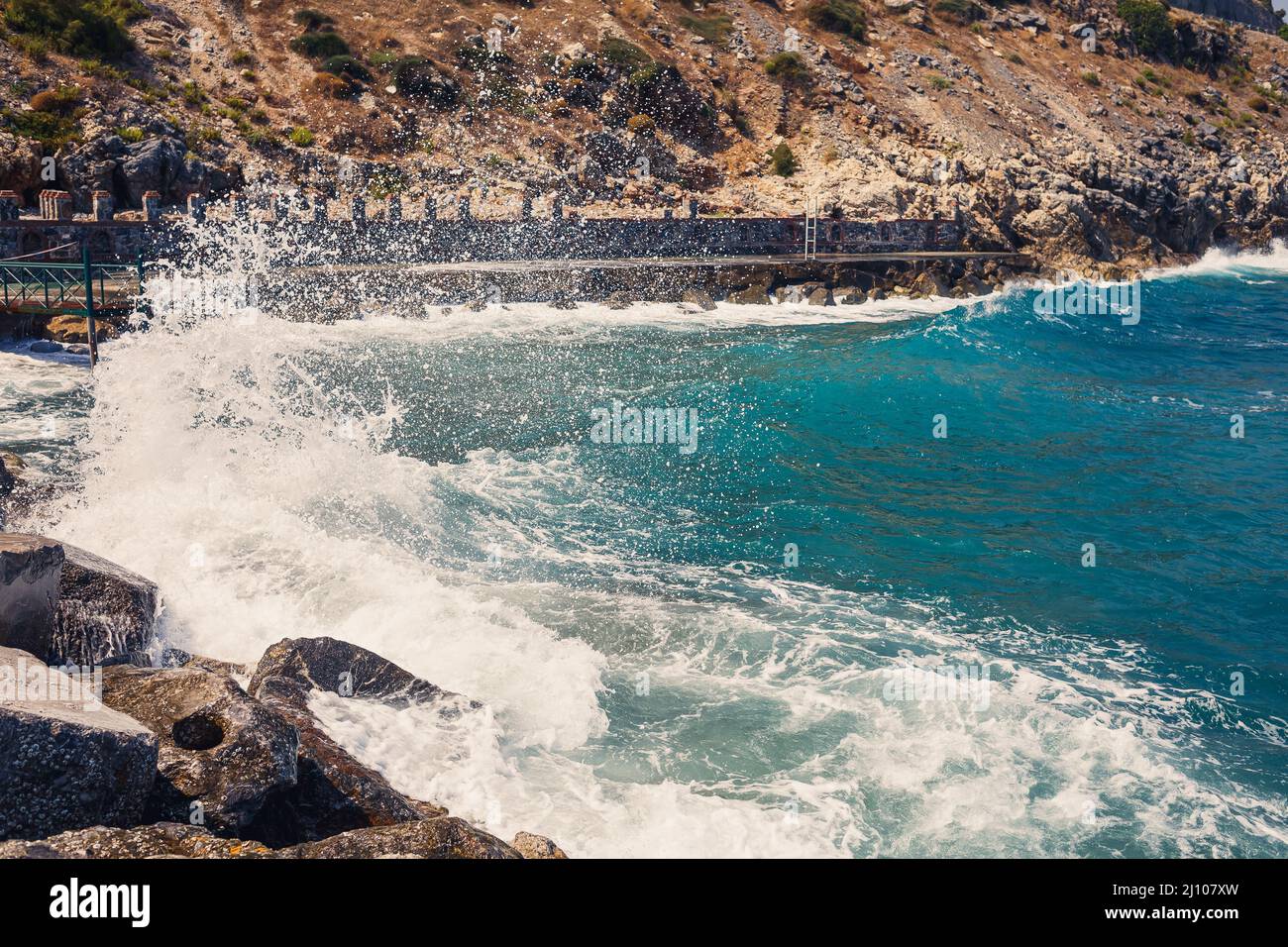 Sea water beats against rocky rocks and makes waves with foam, rugged ...