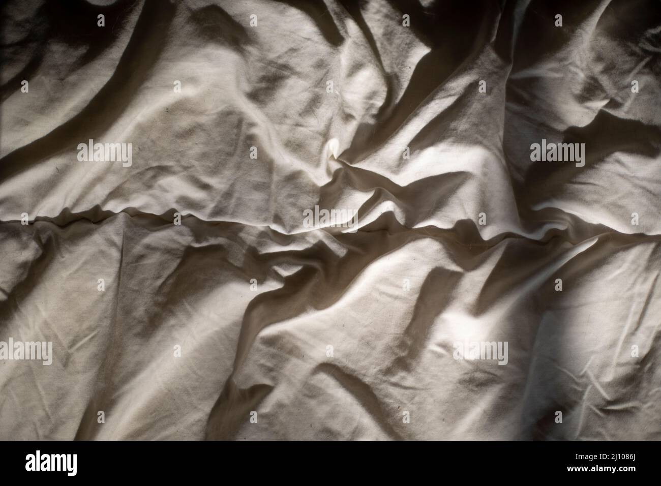 Matting sheet on bed. Texture of fabric in sunlight. Folds on bed linen ...