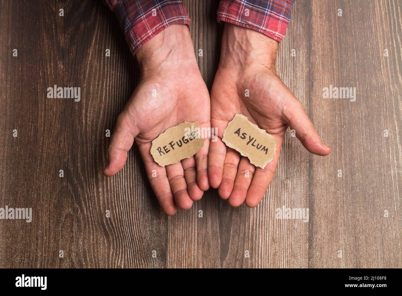 Man holding two pieces of paper with refugee and asylum write in them ...