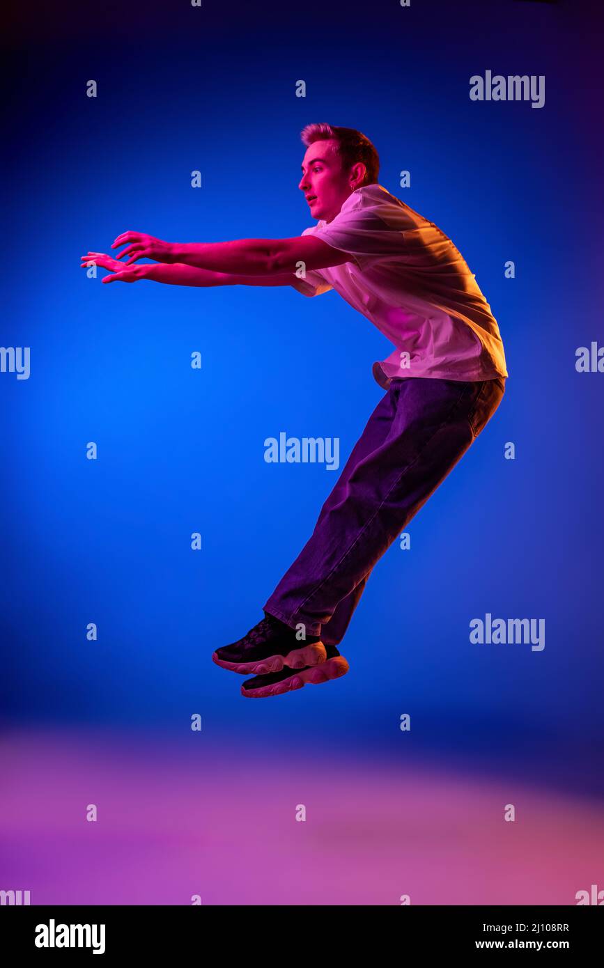 Full-length portrait of young man in casual cloth jumping, posing ...