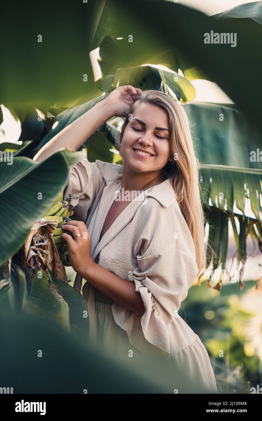 Exotic tropical woman near green leaves of banana bush. Tropical island ...