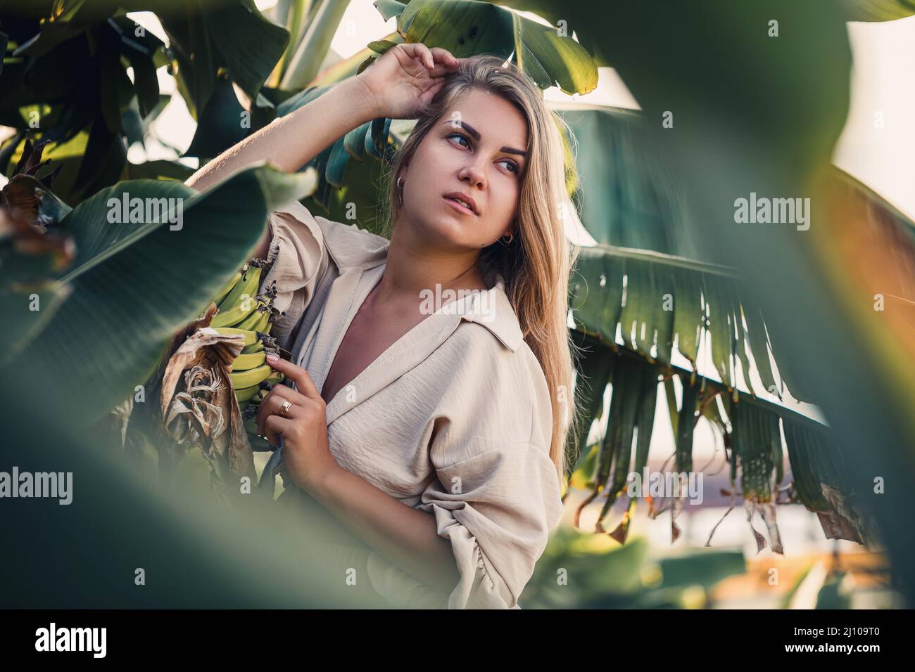 Exotic tropical woman near green leaves of banana bush. Tropical island ...