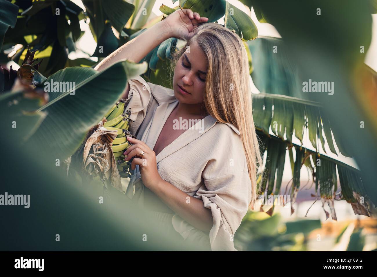 Exotic tropical woman near green leaves of banana bush. Tropical island ...