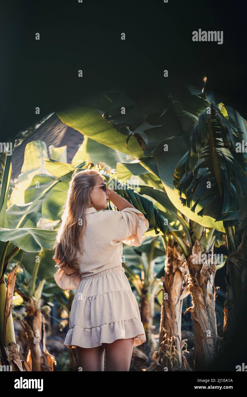 Exotic tropical woman near green leaves of banana bush. Tropical island ...