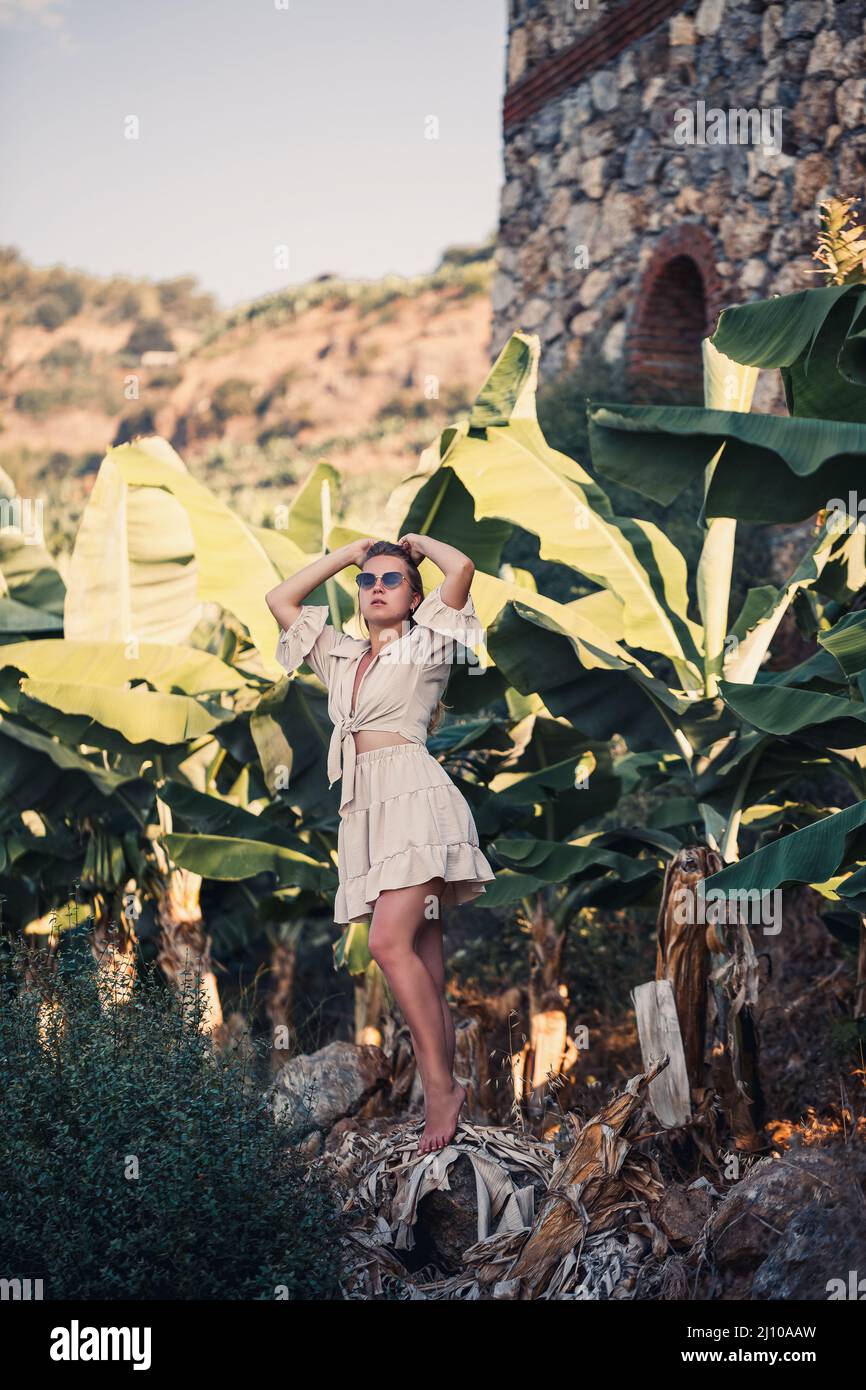 Exotic tropical woman near green leaves of banana bush. Tropical island ...