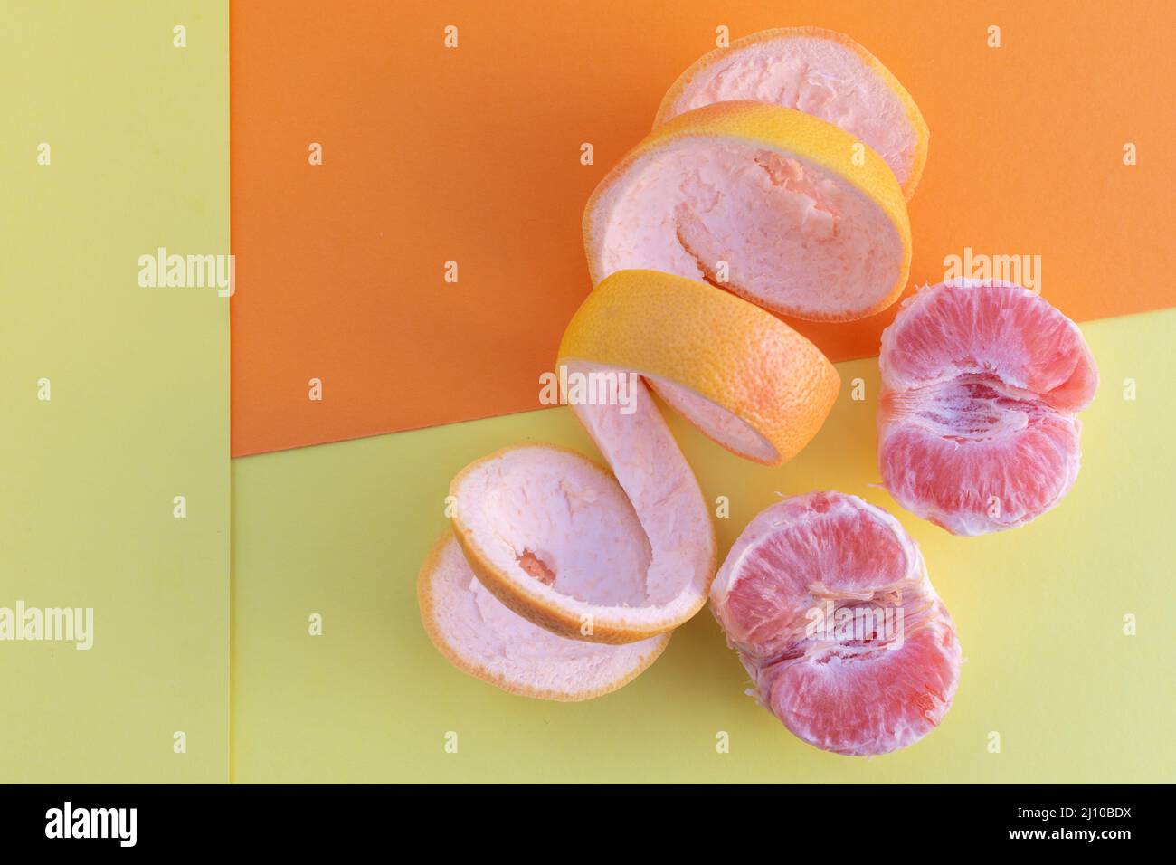 A peeled grapefruit on a yellow and orange background Stock Photo - Alamy