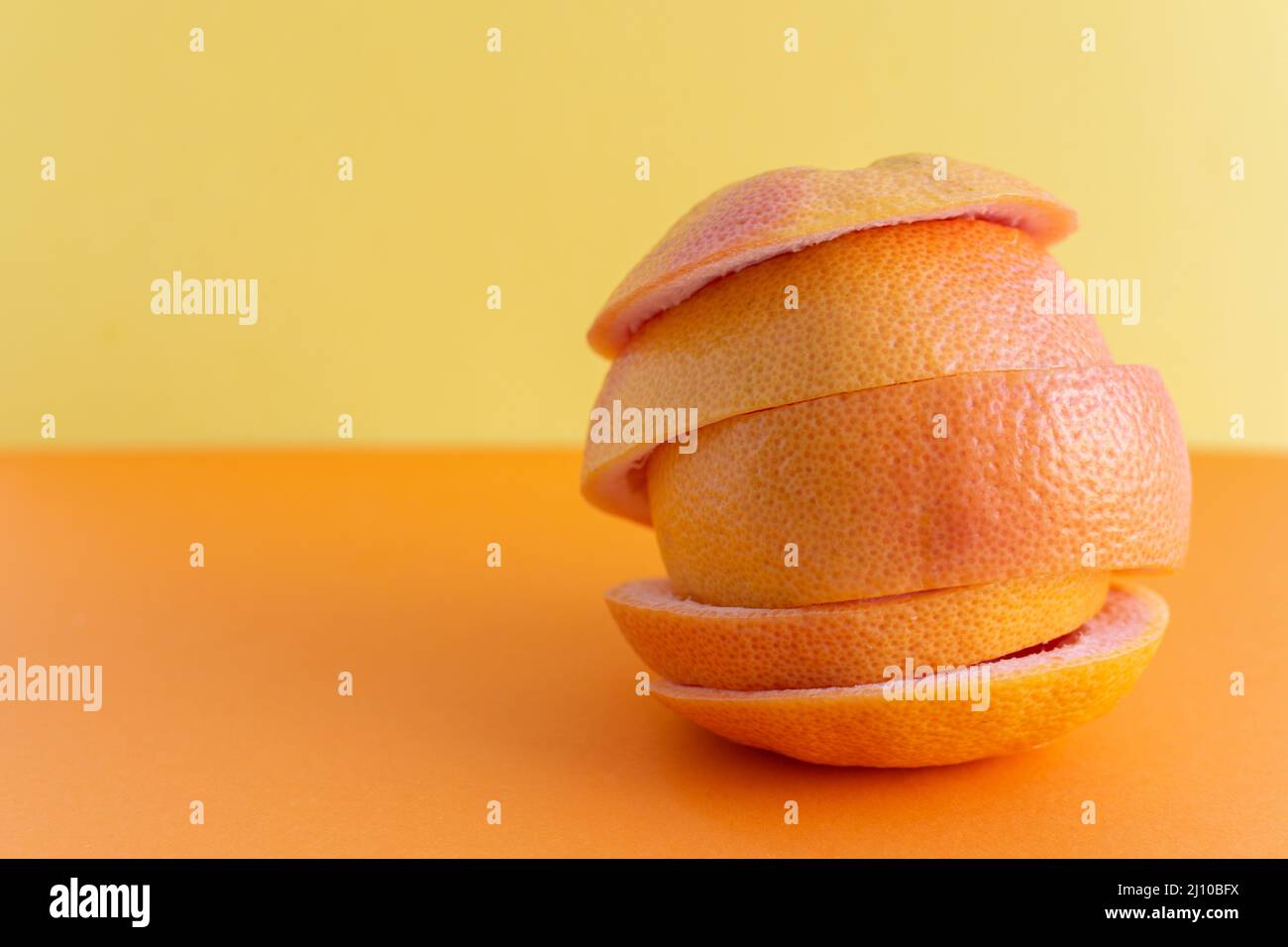 A peeled grapefruit on a yellow and orange background Stock Photo - Alamy