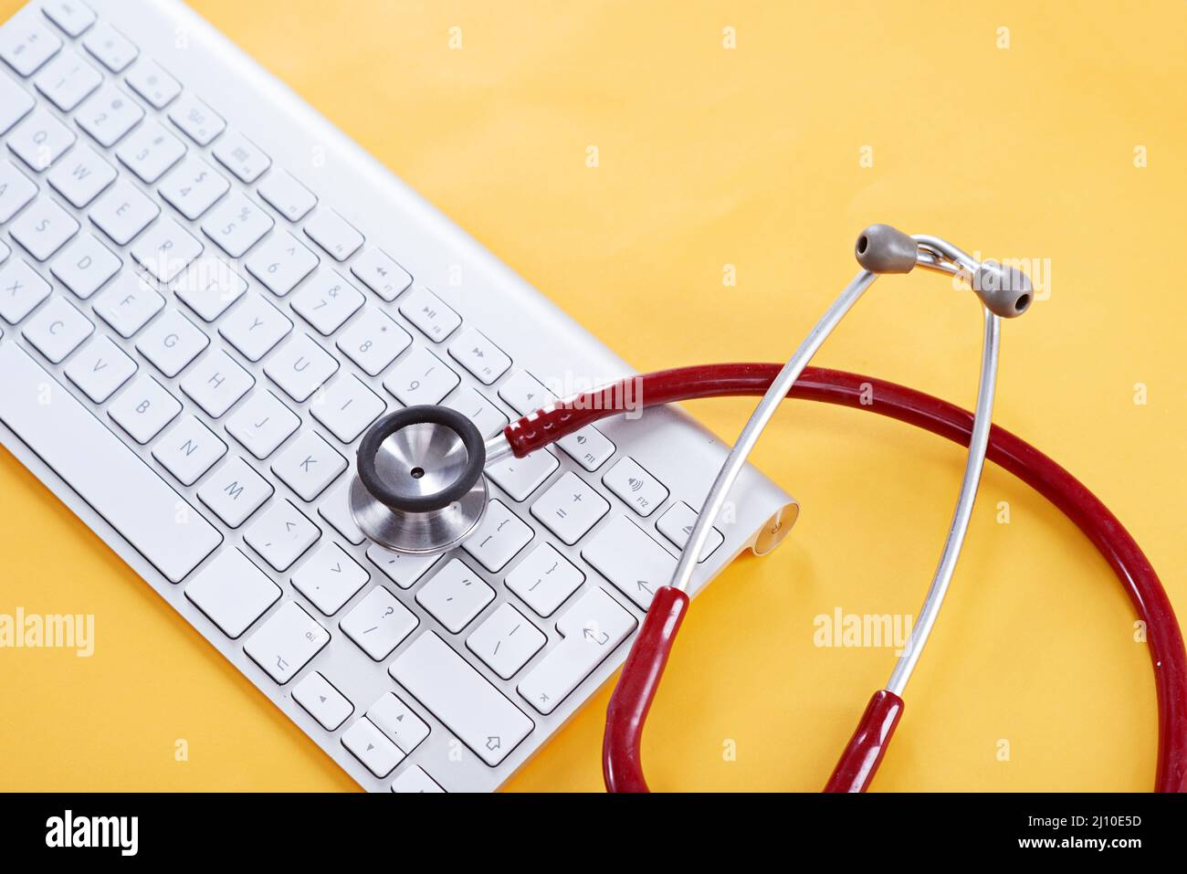 Computer care. Concept shot of a keyboard and stethoscope on a yellow ...