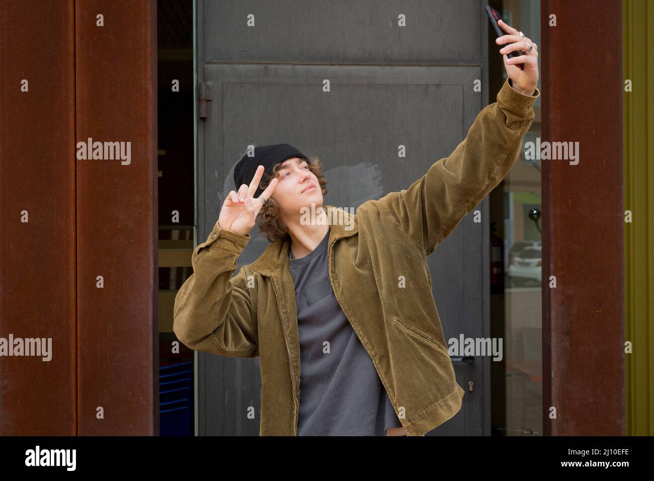teenager with a cap taking a photo with a cell phone in the street ...
