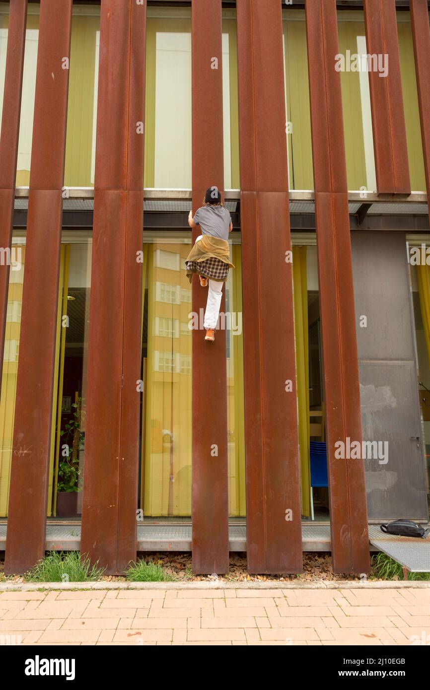 young man climbing a steel building facade Stock Photo - Alamy