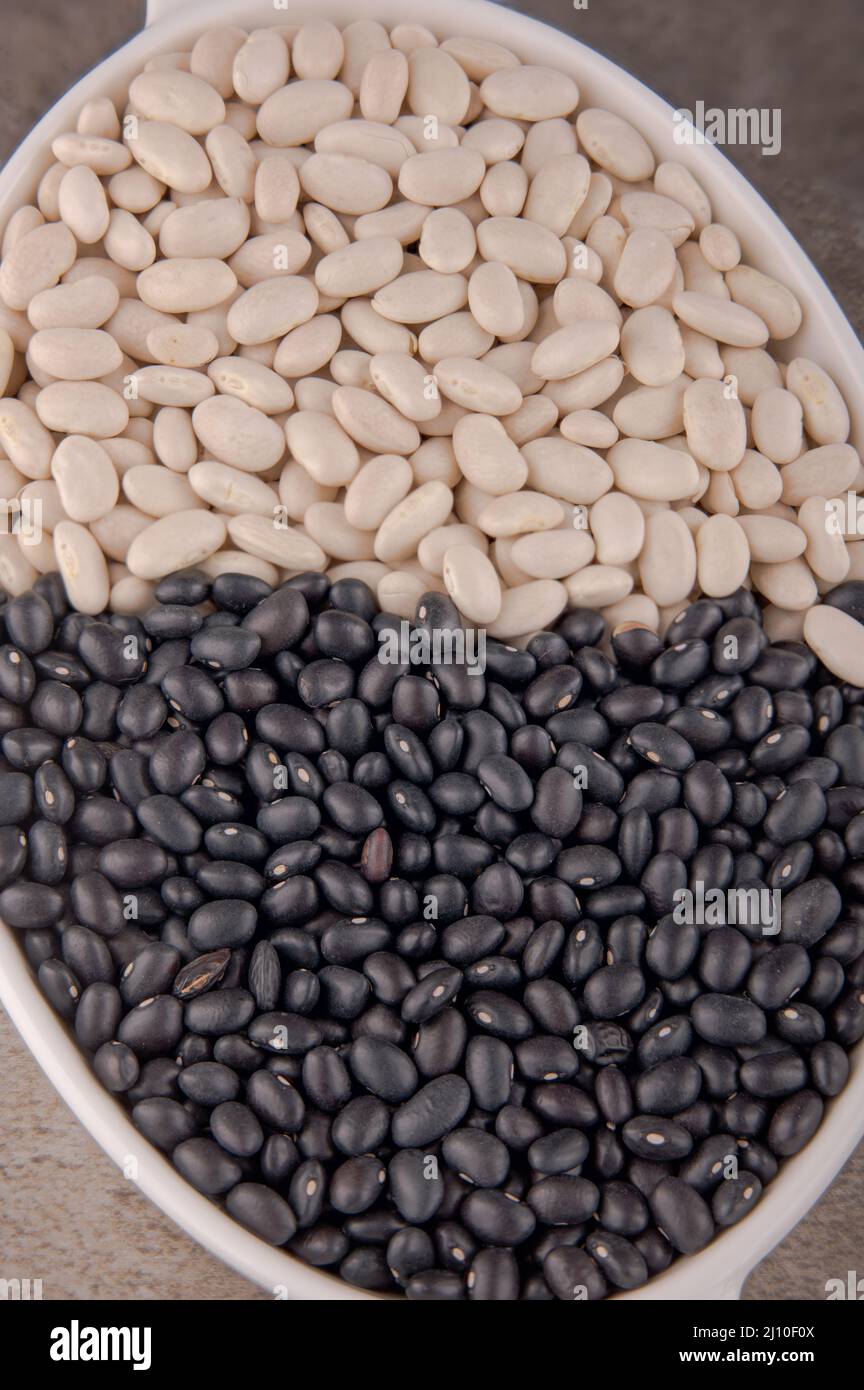 The photo shows black and white beans. The texture of the seeds is made ...